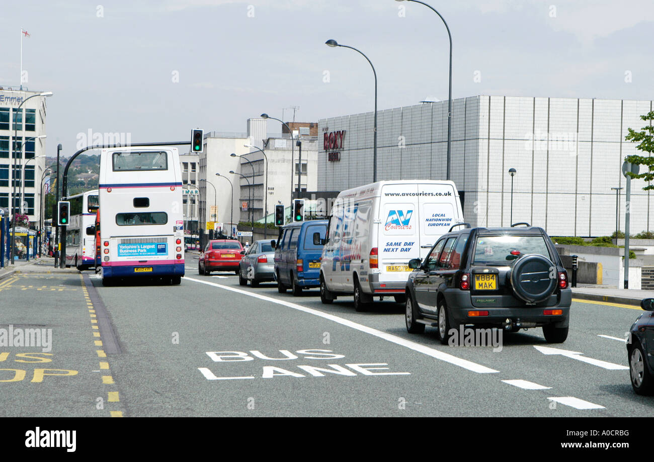 Bus passing queues of traffic as it travels along a bus lane in ...