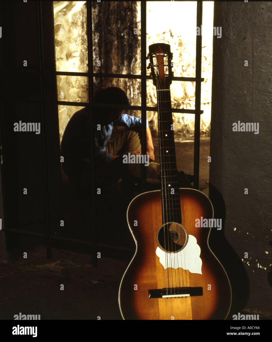 Man In Jail with Guitar Leaning against Bars Stock Photo - Alamy