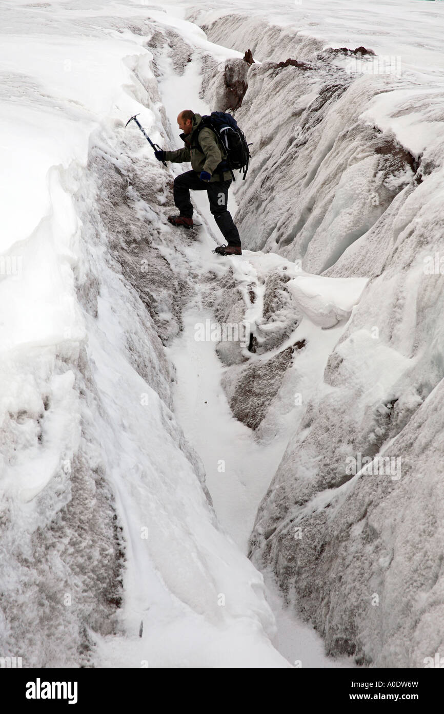 Climber crossing small crevasse on Ortsveri Glacier. Mount Kazbek ...