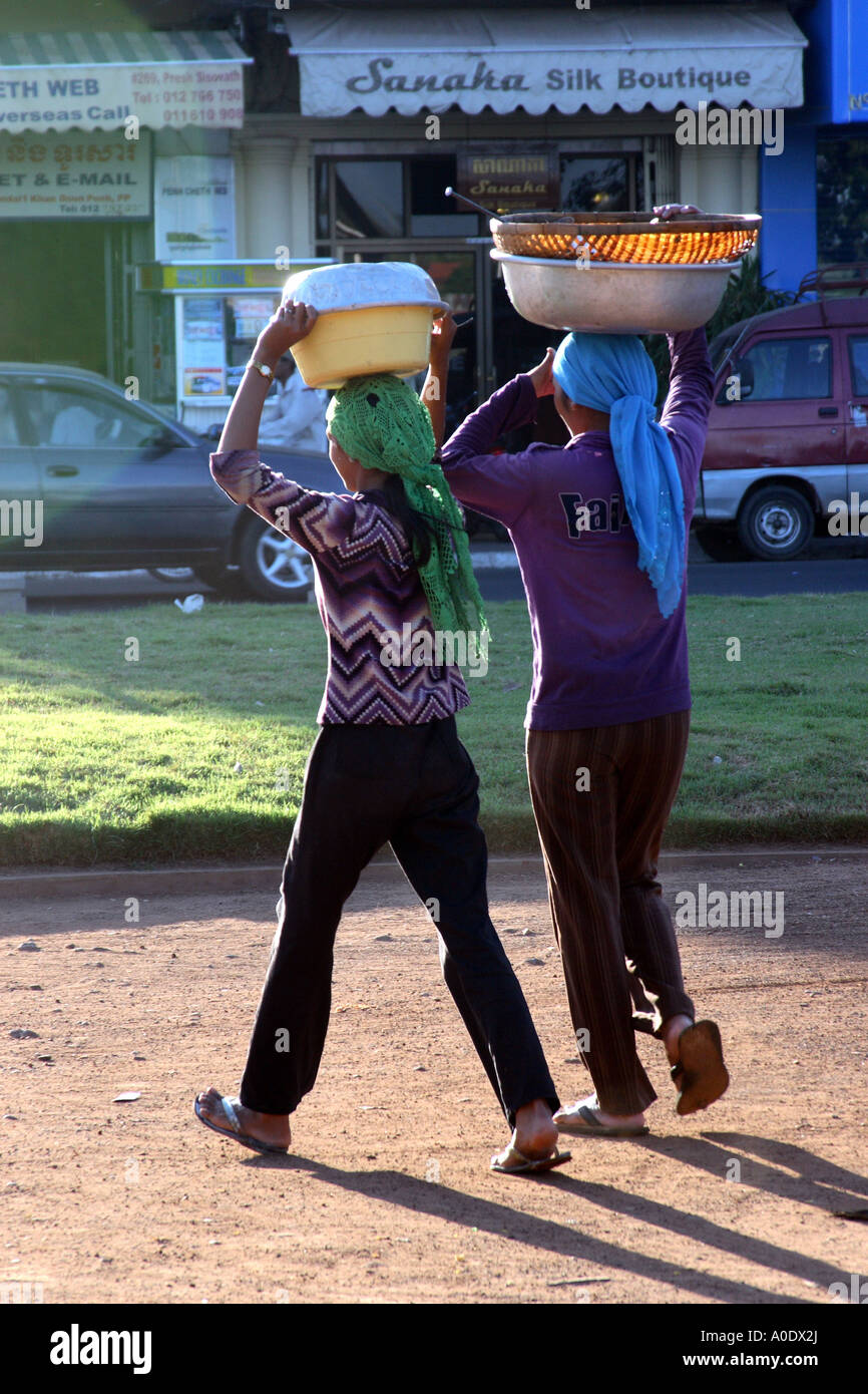 Women carrying food in baskets on their heads in the Cambodian capital ...