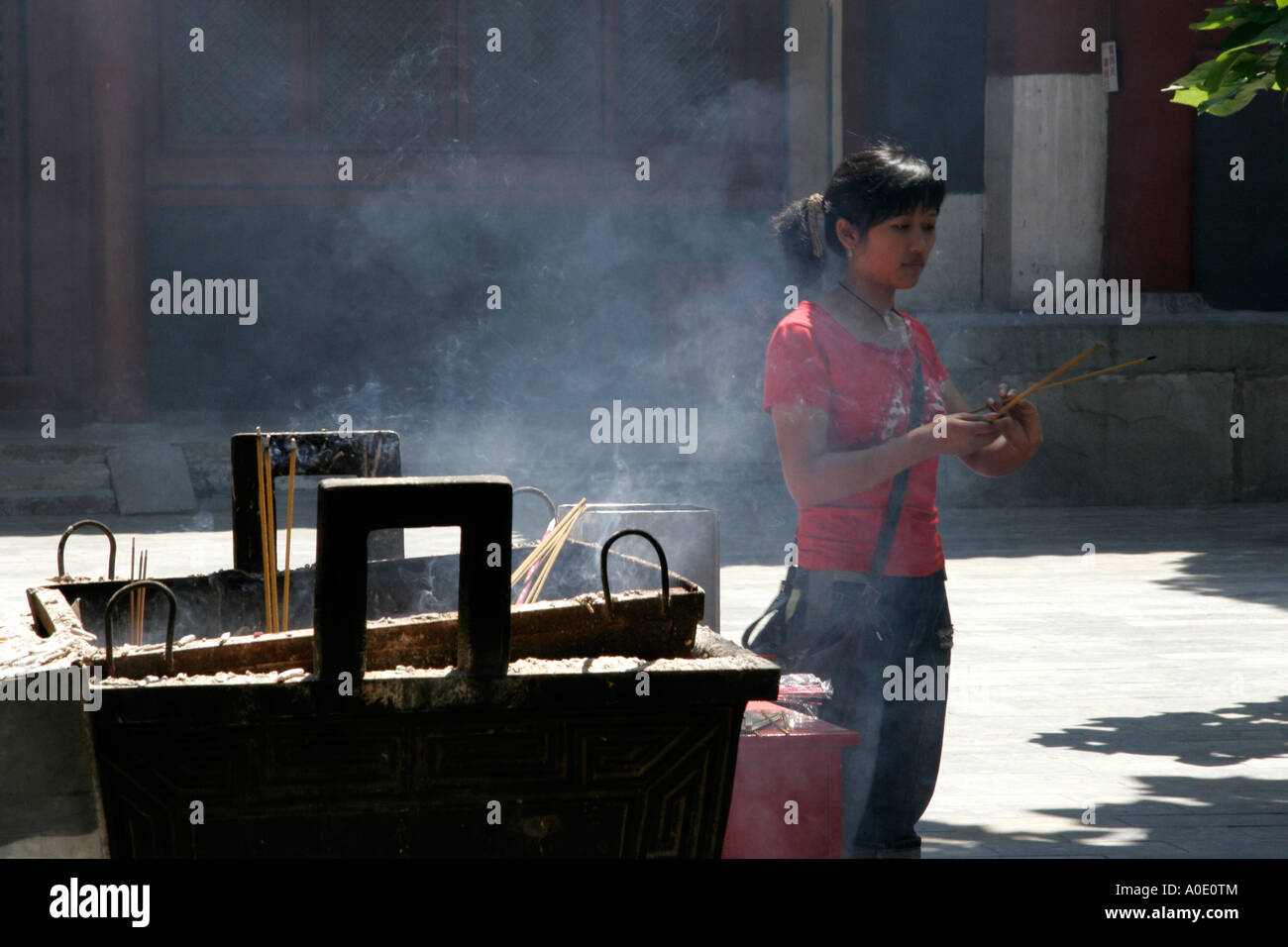 A young girl making an offering in the 17th century Tibetan Lama Temple ...
