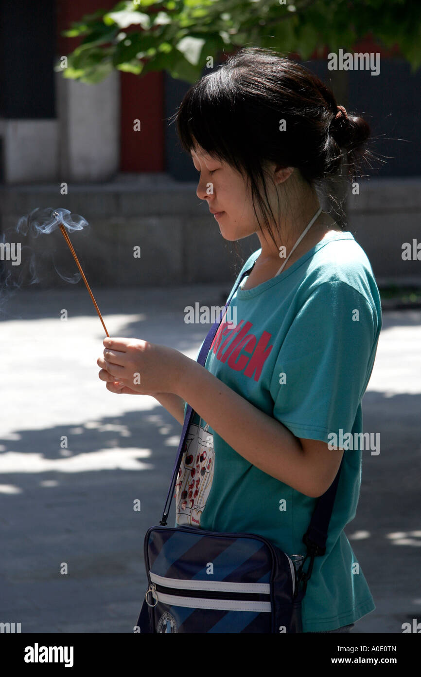A young girl making an offering in the 17th century Tibetan Lama Temple ...