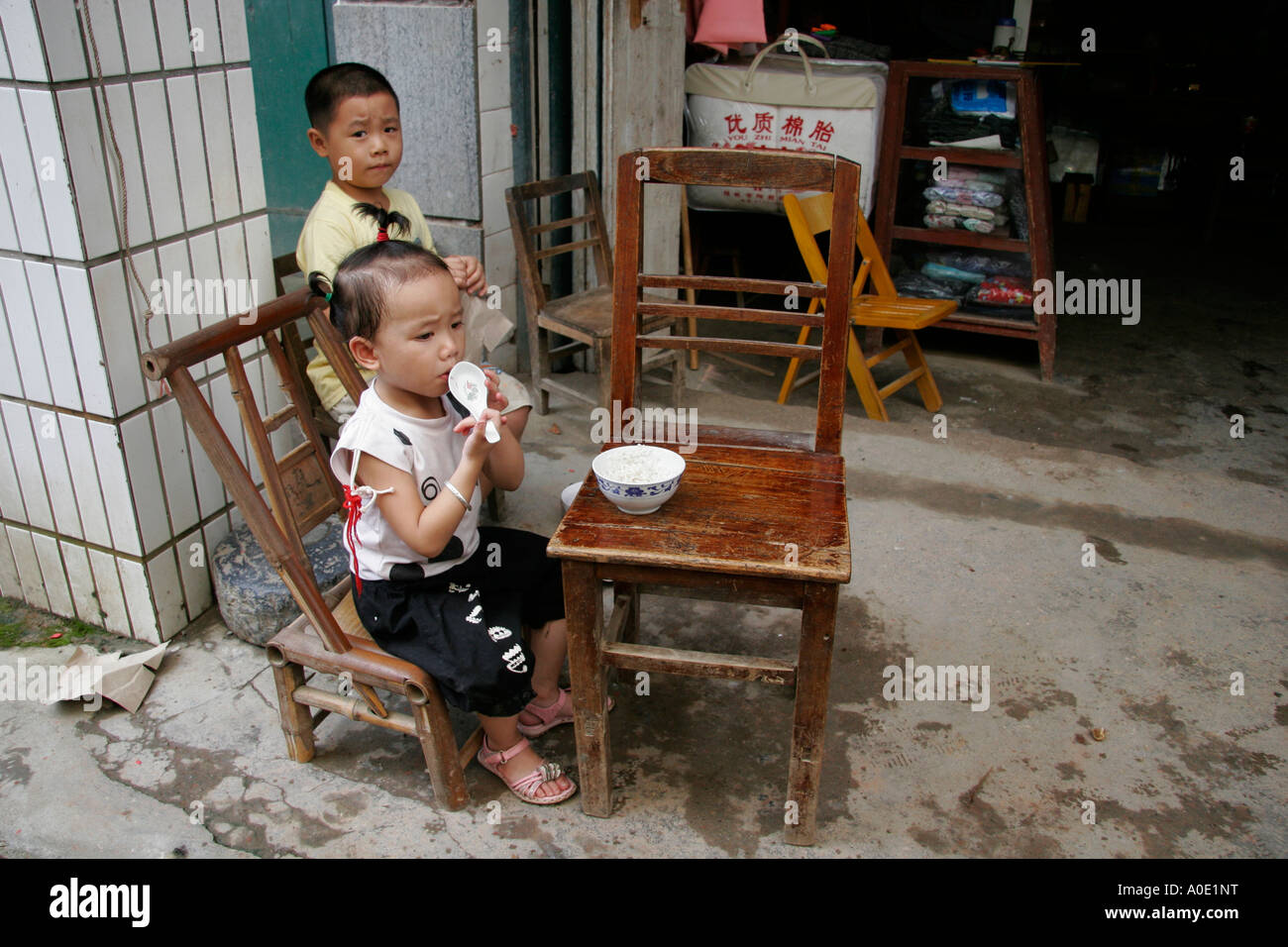 A small child eating rice outside a small store in Rural China Stock ...