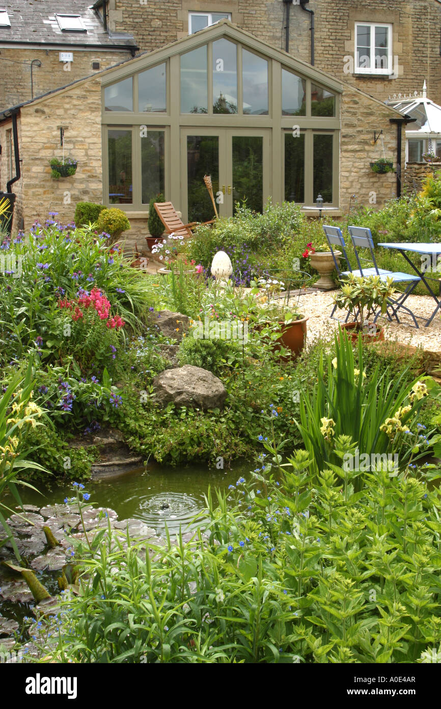 UK garden pond feature with garden room conservatory beyond Stock Photo ...