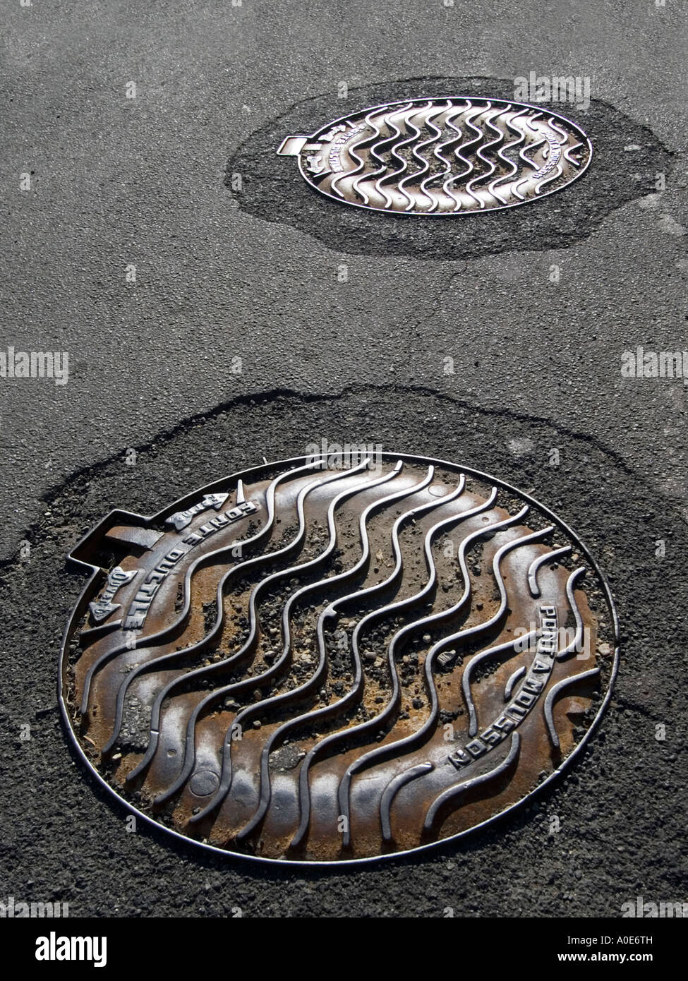two cast-iron manhole covers in a street in St Amant de Boix Poitou ...