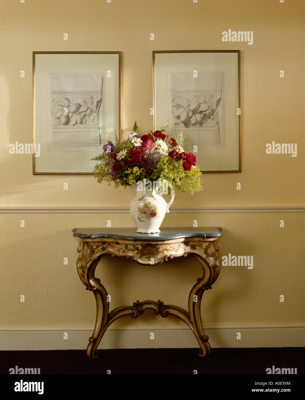 Flower arrangement on antique console table beneath pictures Stock ...