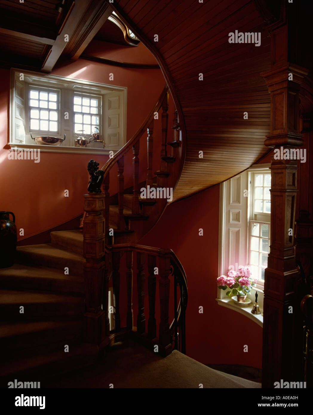 Wooden spiral staircase in red hall Stock Photo - Alamy