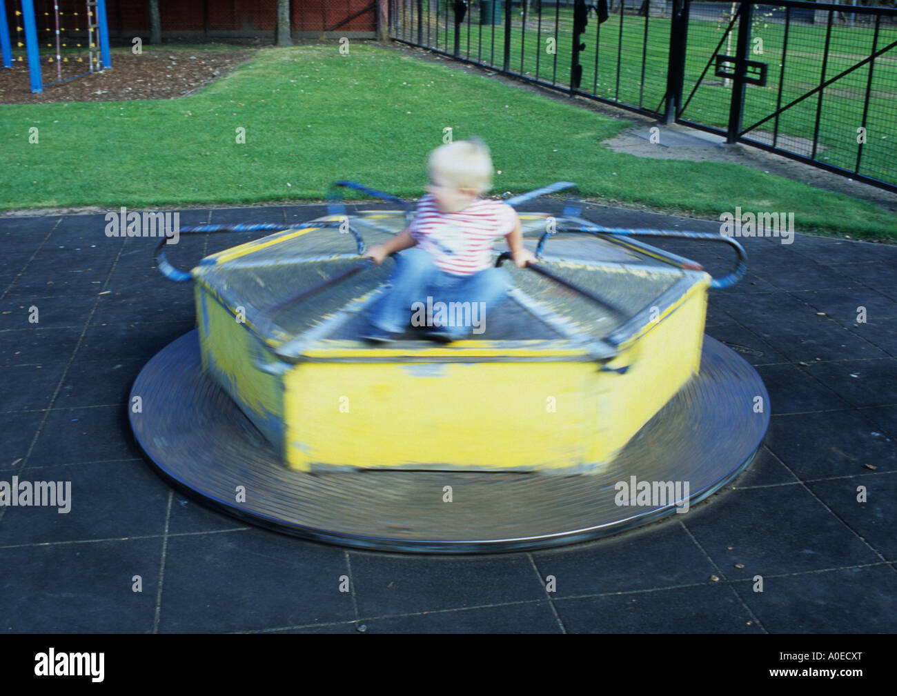 Three Year Old Boy On Roundabout in the uk Stock Photo - Alamy