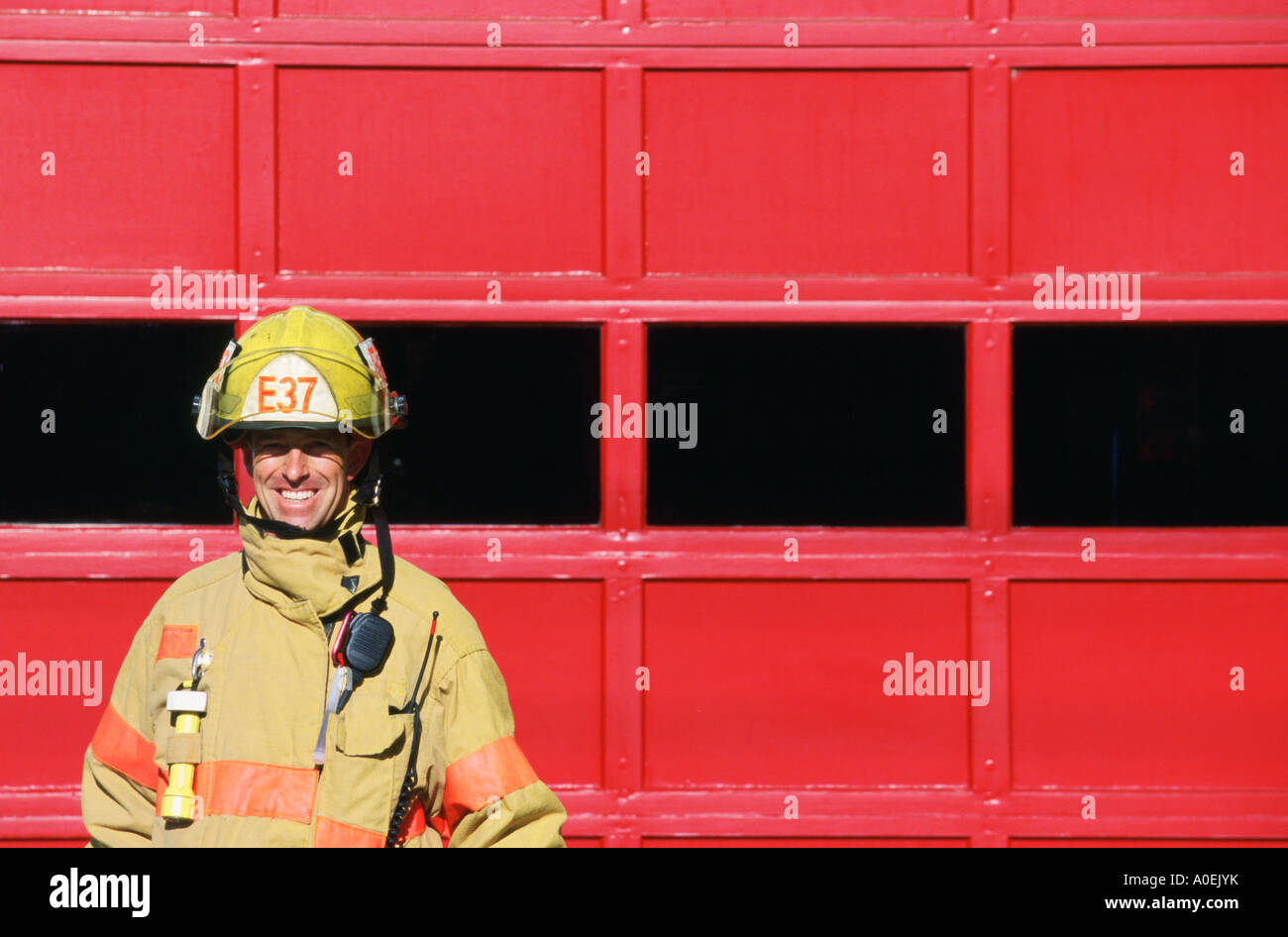 Portrait of smiling male firefighter with red garage door Stock Photo ...