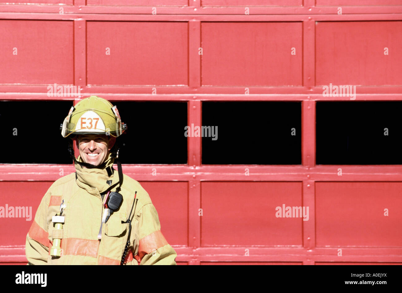 Portrait of smiling male firefighter with red garage door Stock Photo ...