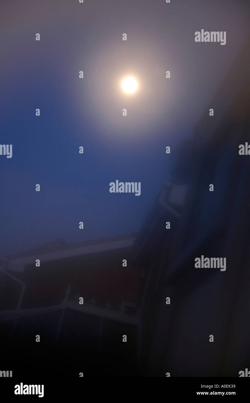 Full moon at night above the rooftops of residential dwellings on a ...