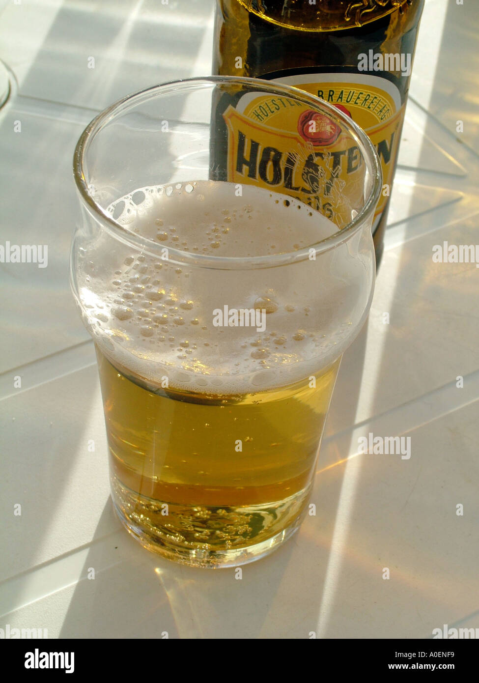 Glass half full of lager in sunshine at seaside cafe Stock Photo - Alamy