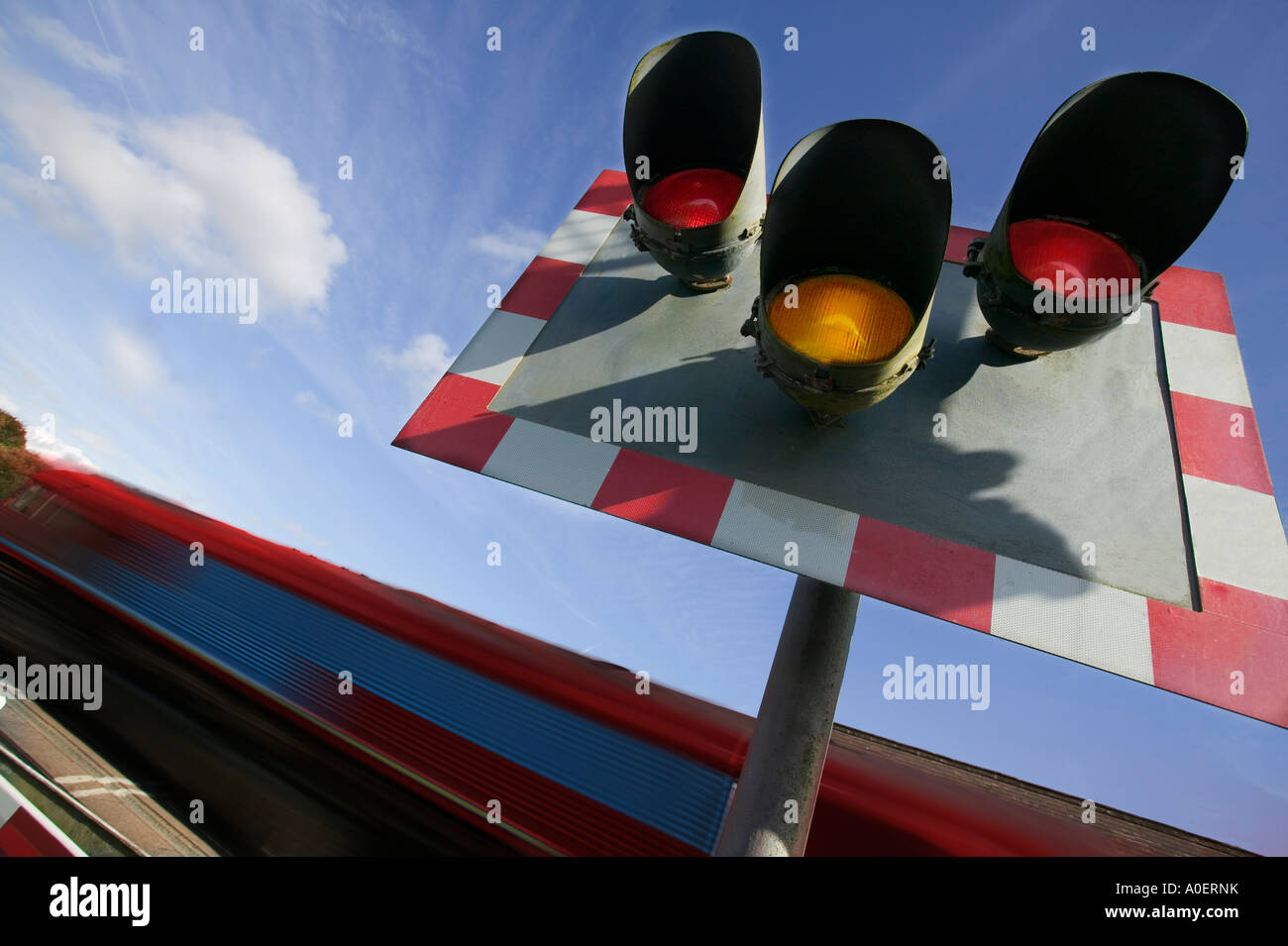 DANGER SIGNALS ON RAILWAY CROSSING WITH SPEEDING TRAIN PASSING UK Stock ...