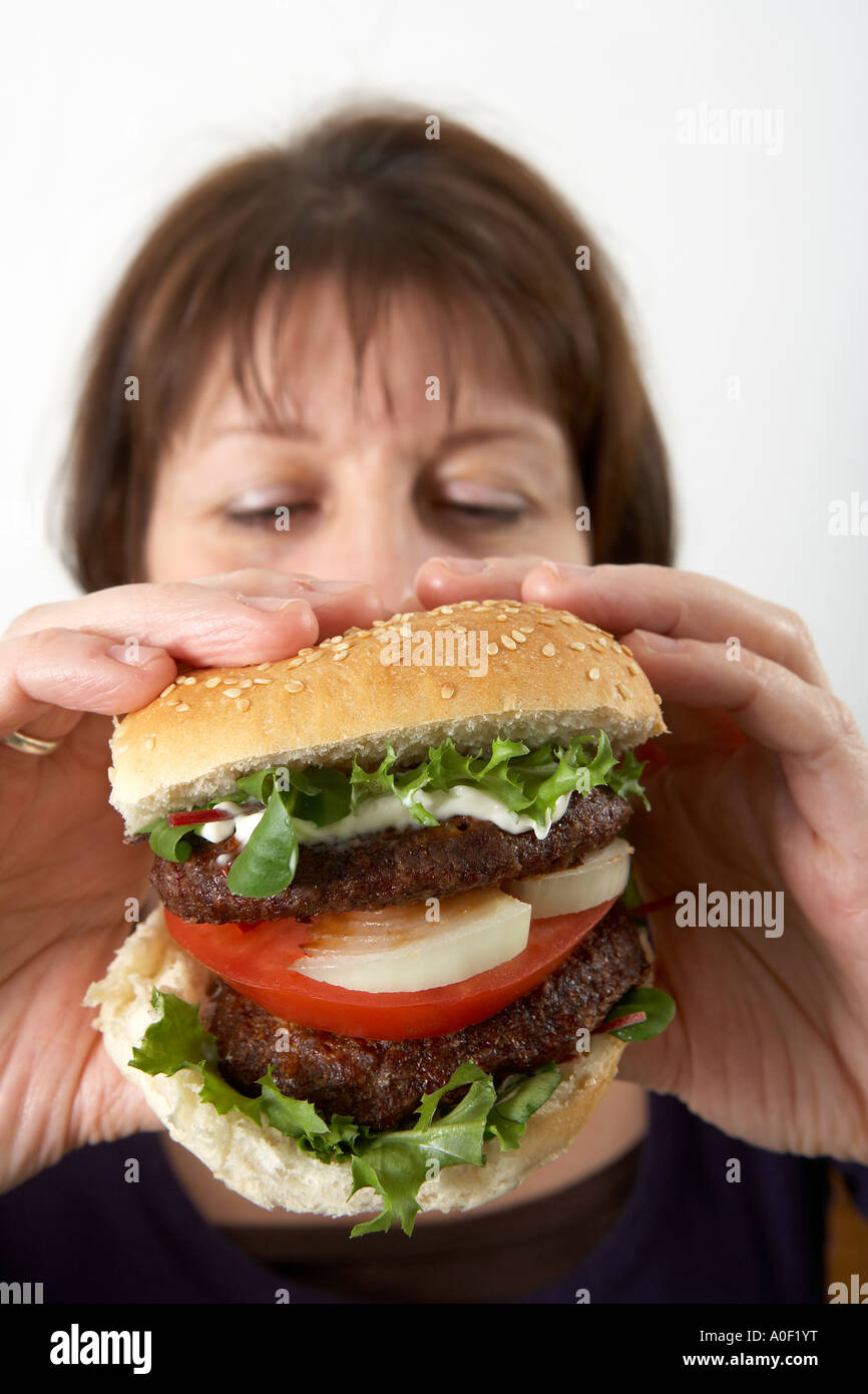 Woman eating a double cheeseburger Stock Photo - Alamy