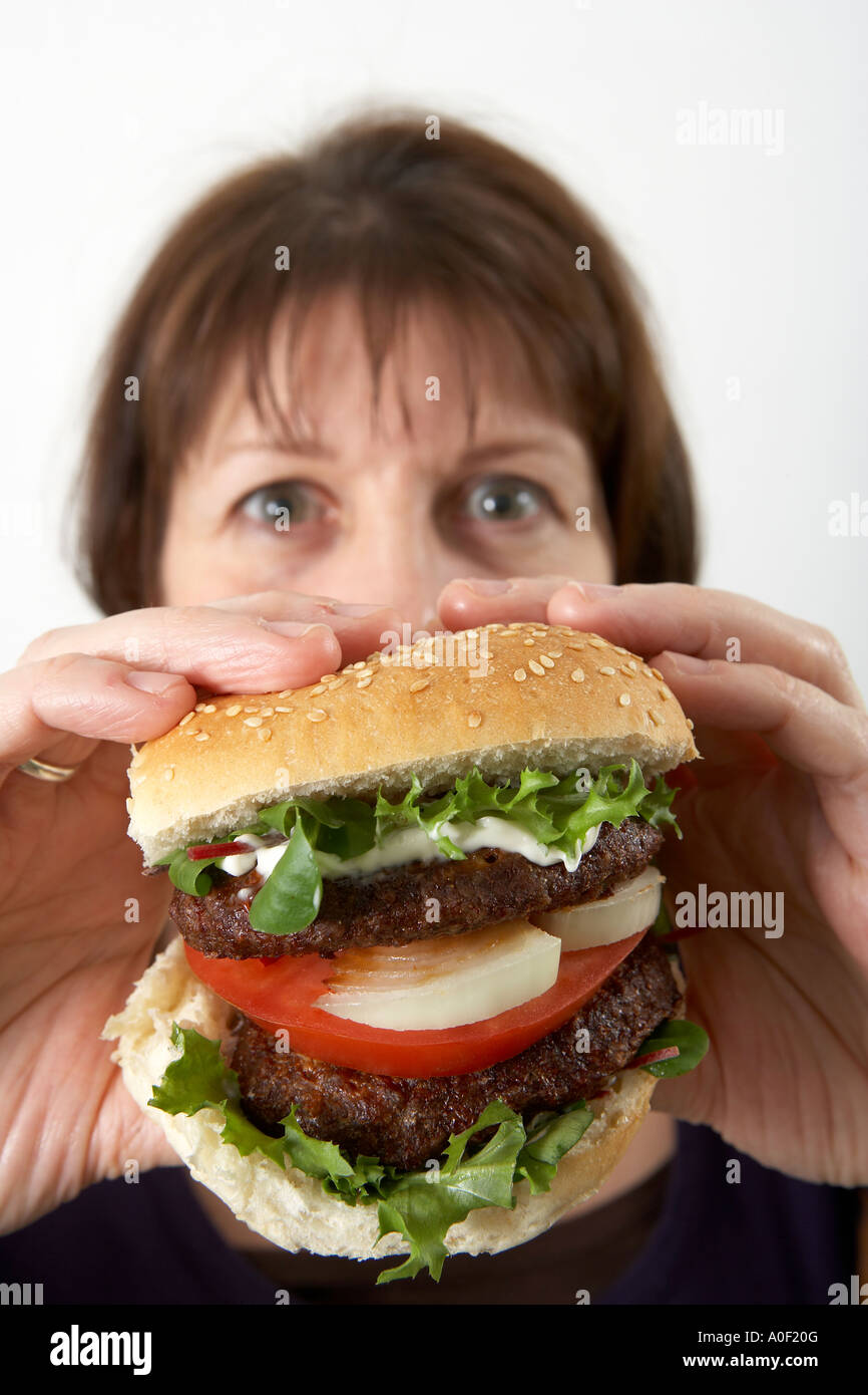 Woman eating a double cheeseburger Stock Photo - Alamy