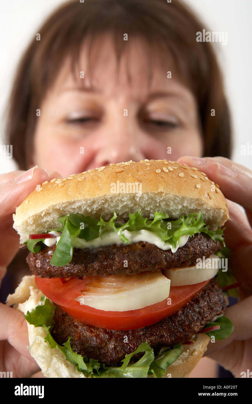Woman eating a double cheeseburger Stock Photo - Alamy