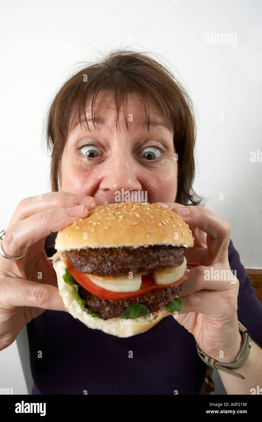 Woman eating a double cheeseburger Stock Photo - Alamy