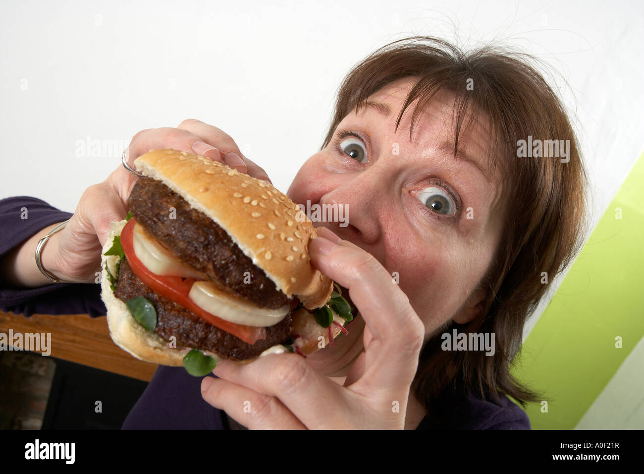 Woman eating a double cheeseburger Stock Photo - Alamy
