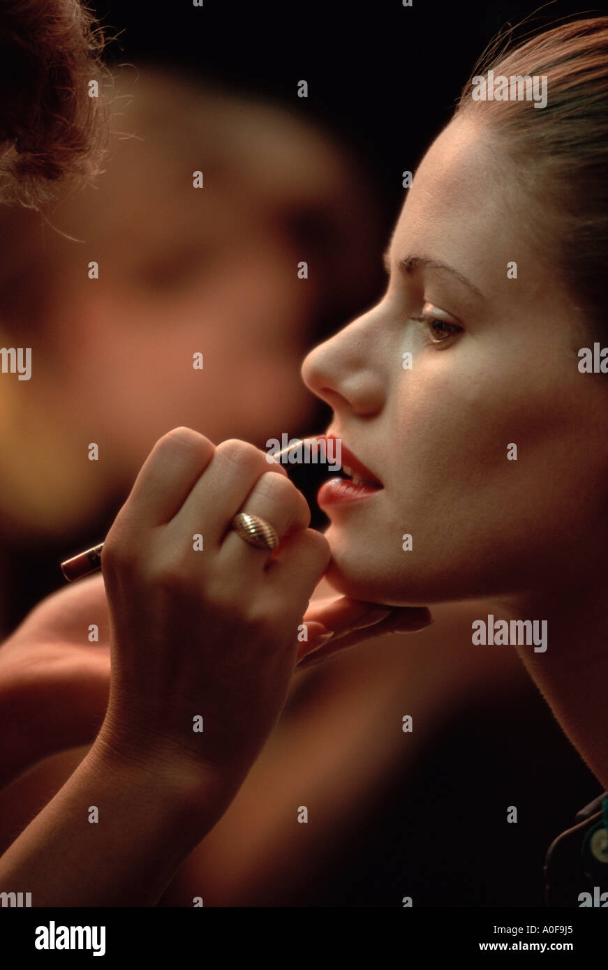 Side profile of a young woman applying lip liner Stock Photo - Alamy