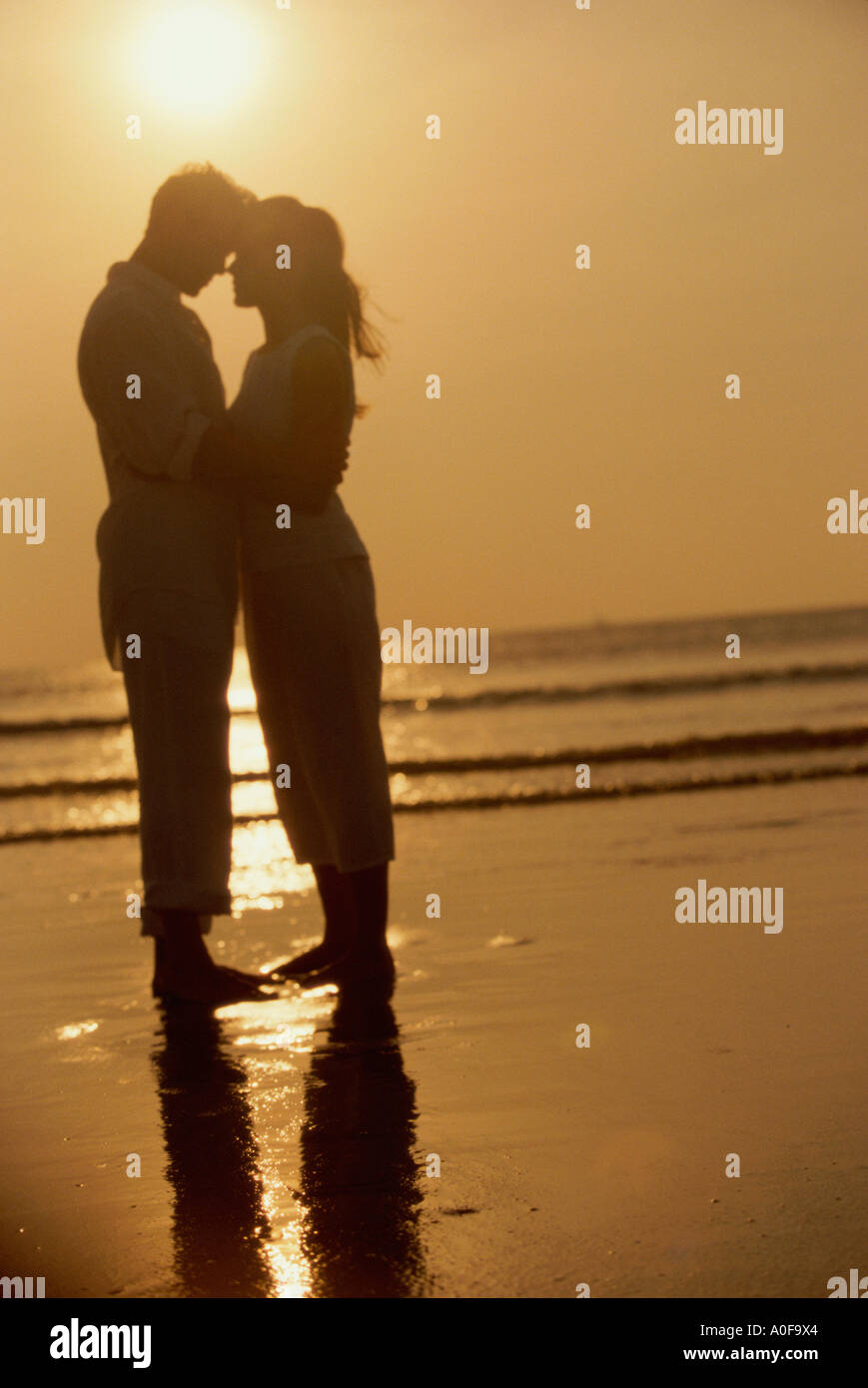 Silhouette of a young couple standing on the beach Stock Photo - Alamy