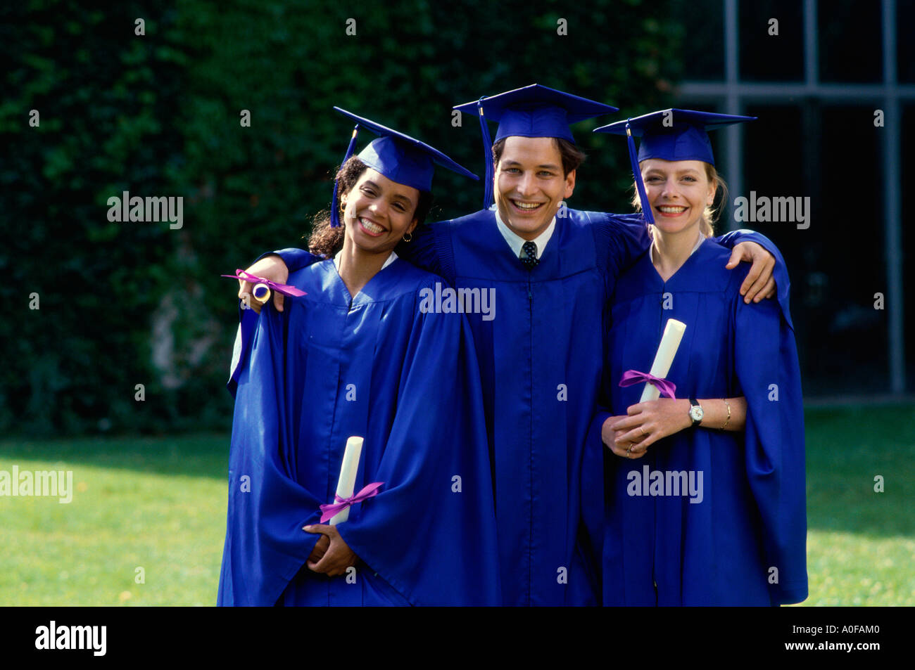 Two female graduates and a male graduate holding diplomas Stock Photo ...