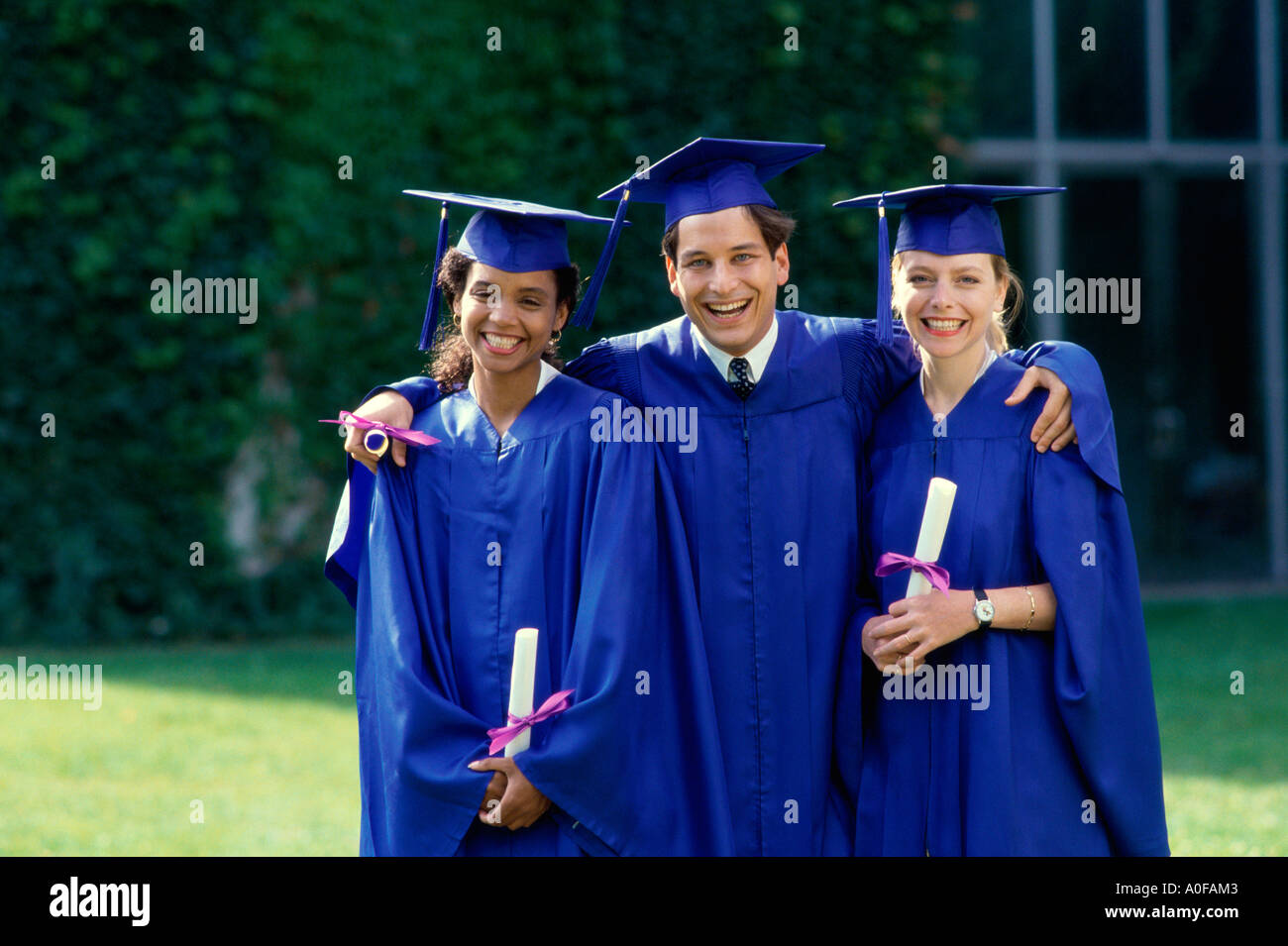 Two female graduates and a male graduate holding diplomas Stock Photo ...