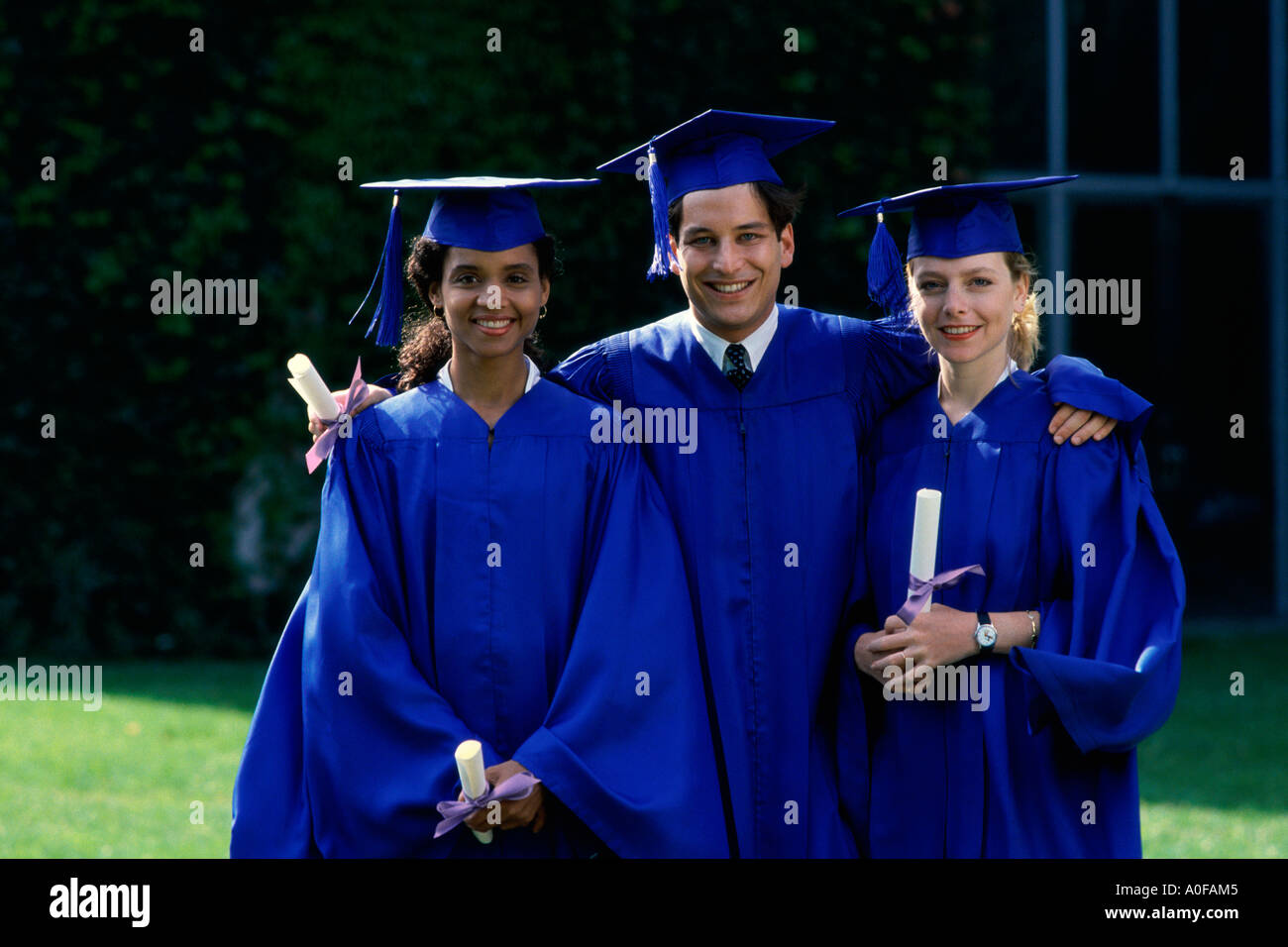 Two female graduates and a male graduate holding diplomas Stock Photo ...