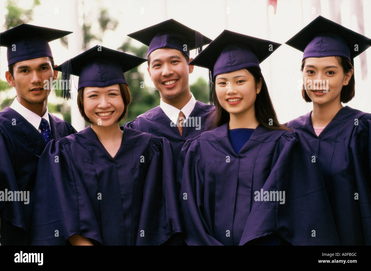 Portrait of three female graduates and two male graduates smiling Stock ...