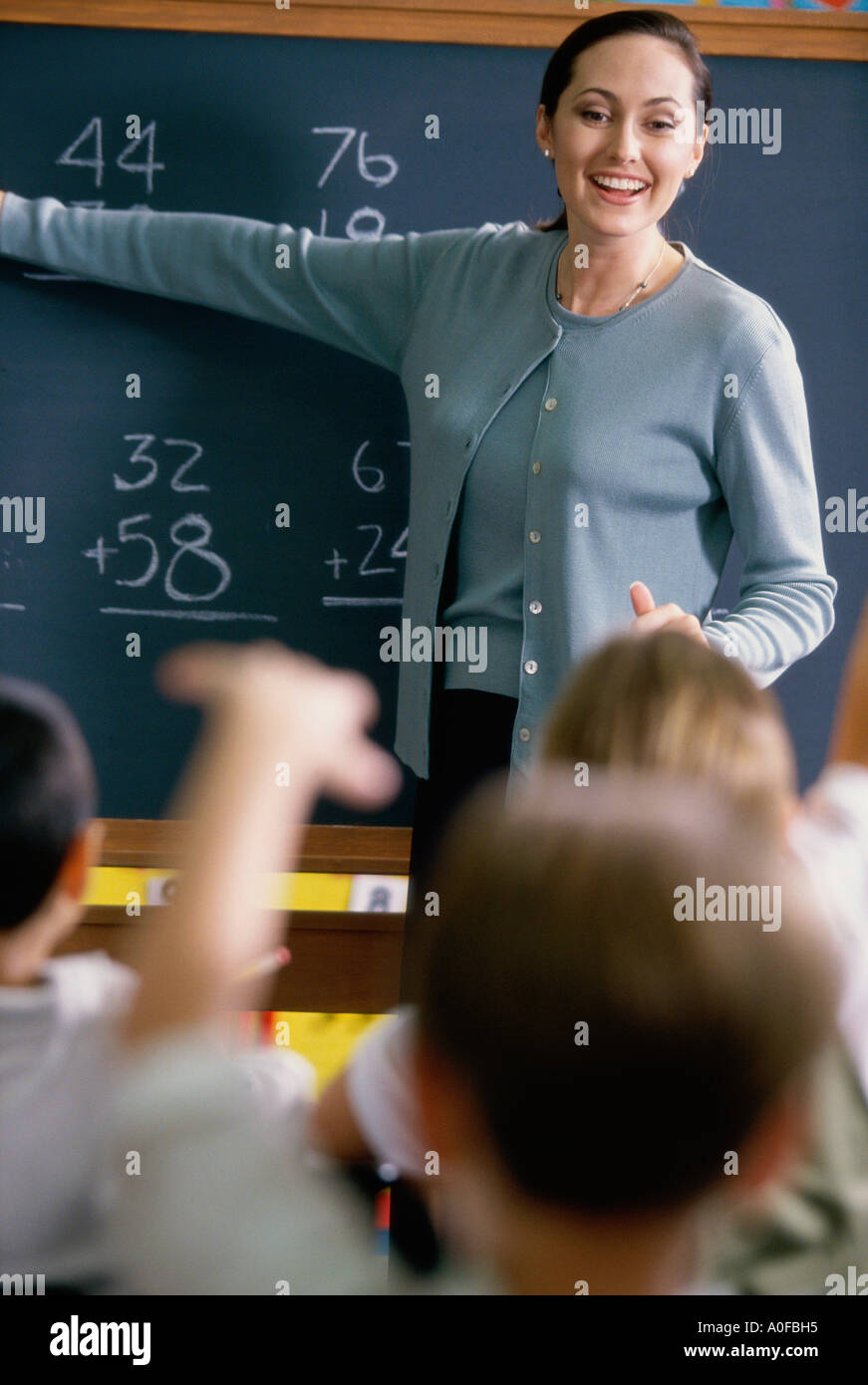 Female teacher pointing to a chalkboard in a classroom Stock Photo - Alamy