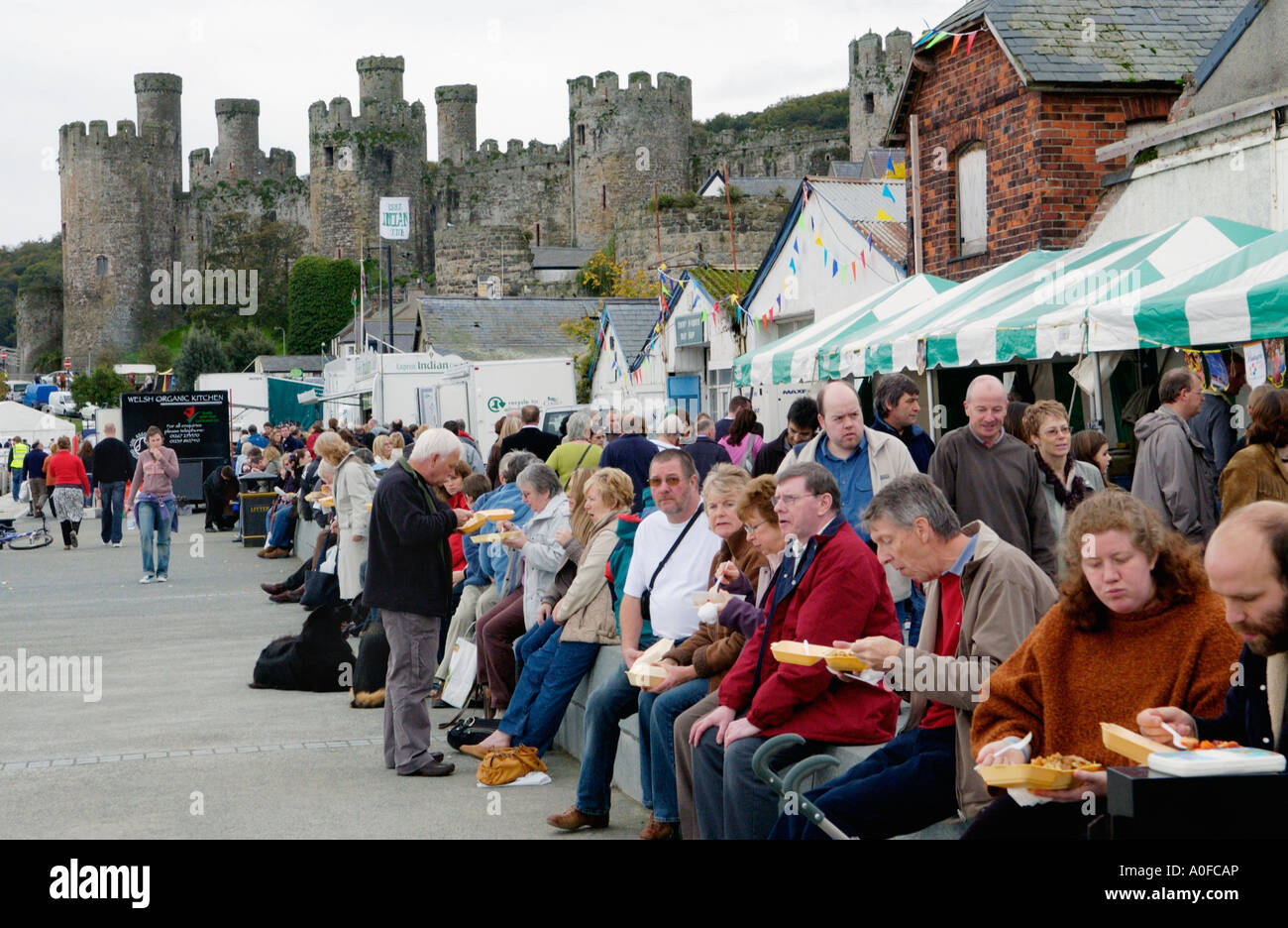 People Eating Fast Food Sat On Quayside Wall At Conwy Food Festival
