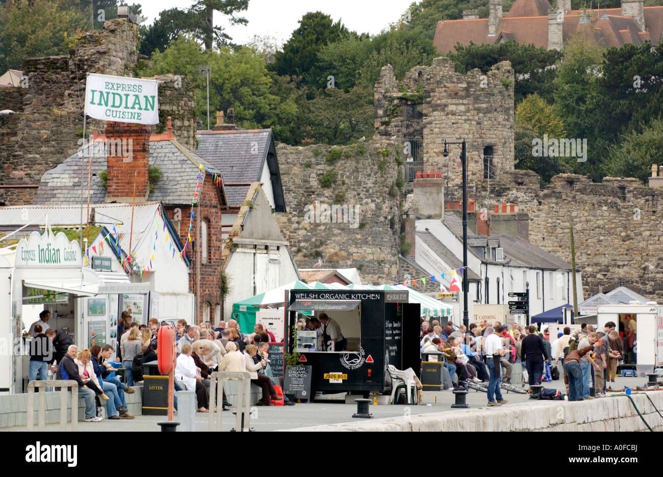 People eating fast food sat on quayside below town wall at Conwy Food ...