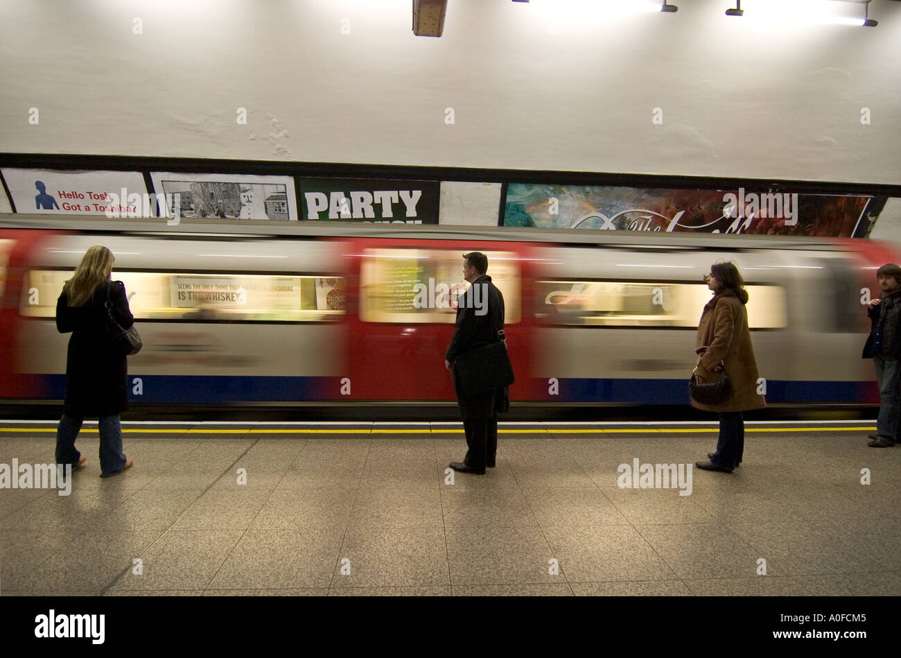 Commuters wait on tube platform as train enters station Stock Photo - Alamy