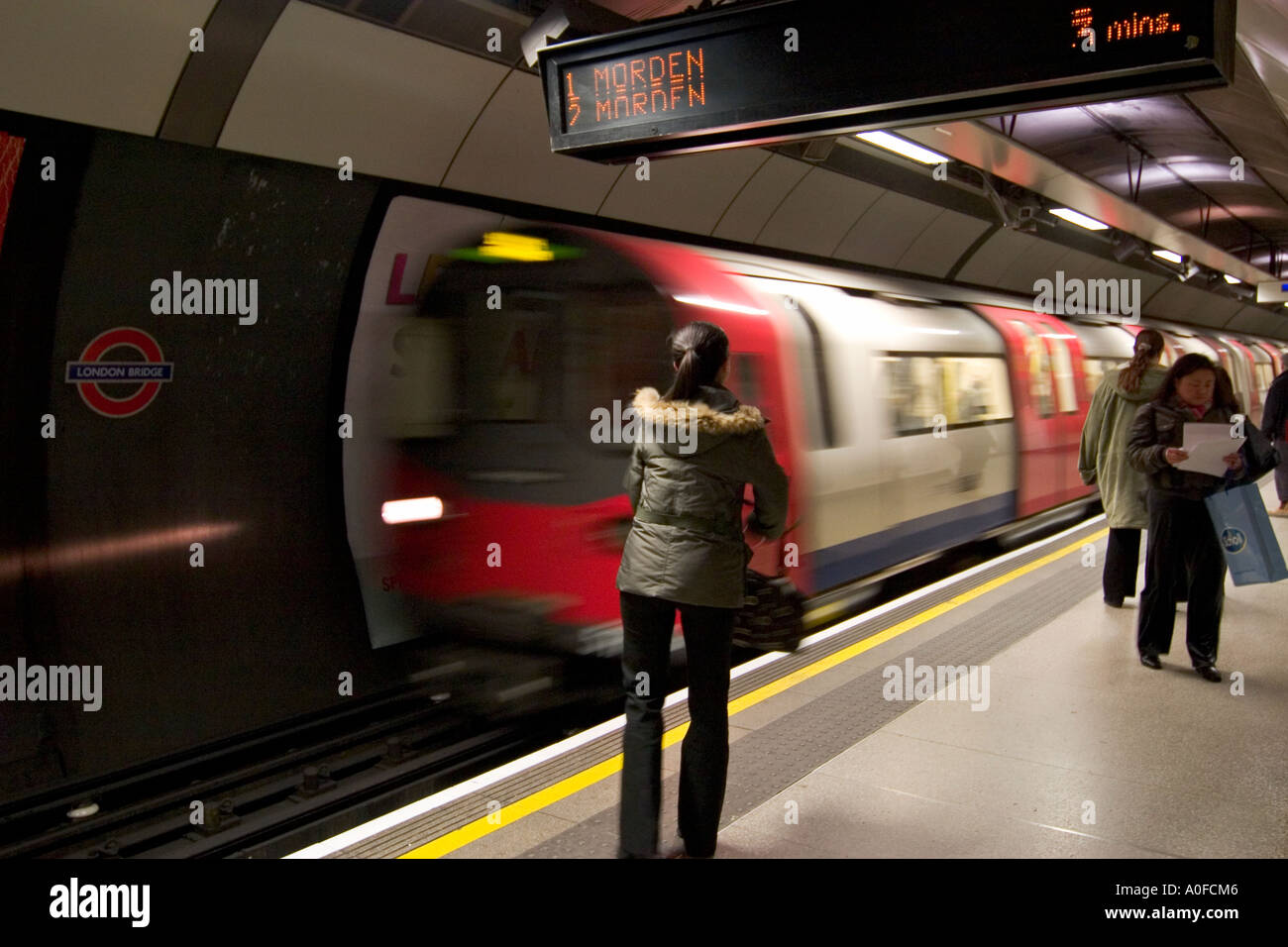Commuters wait on tube platform as train enters station Stock Photo - Alamy