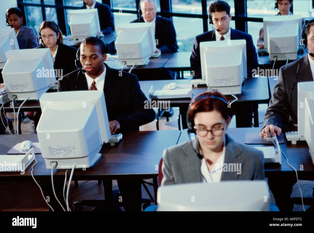 Group of business executives wearing headsets working on computers ...