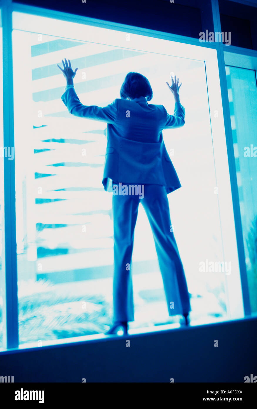 Rear view of a businesswoman leaning against a window Stock Photo - Alamy