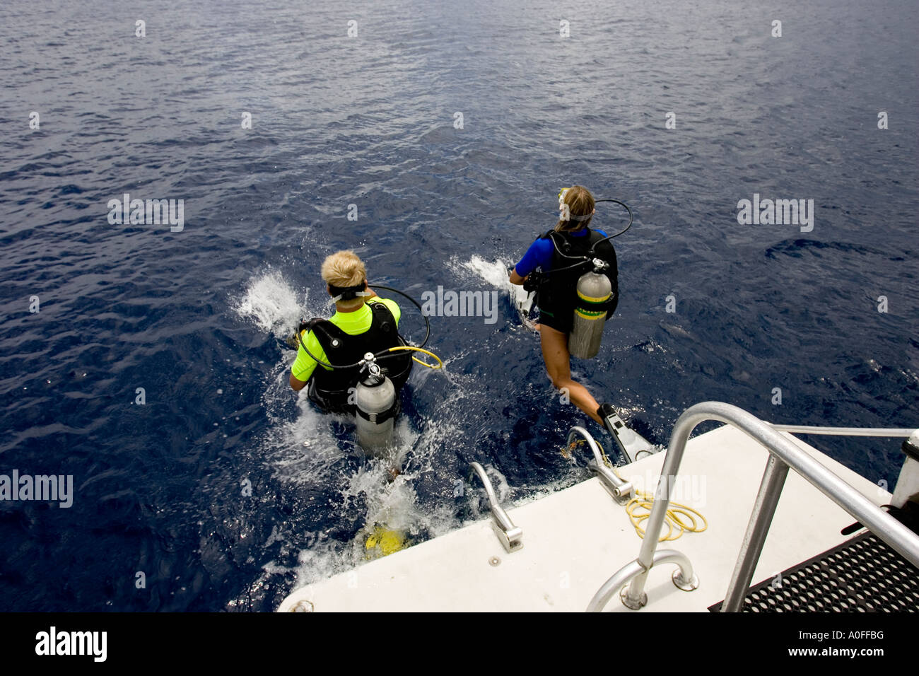A PAIR OF SCUBA DIVERS MAKE A GIANT STRIDE ENTRY FROM THE REAR OF A ...