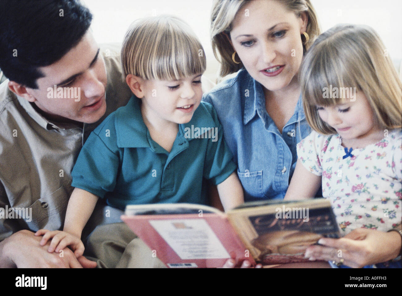 Parents reading a book with their son and daughter Stock Photo - Alamy