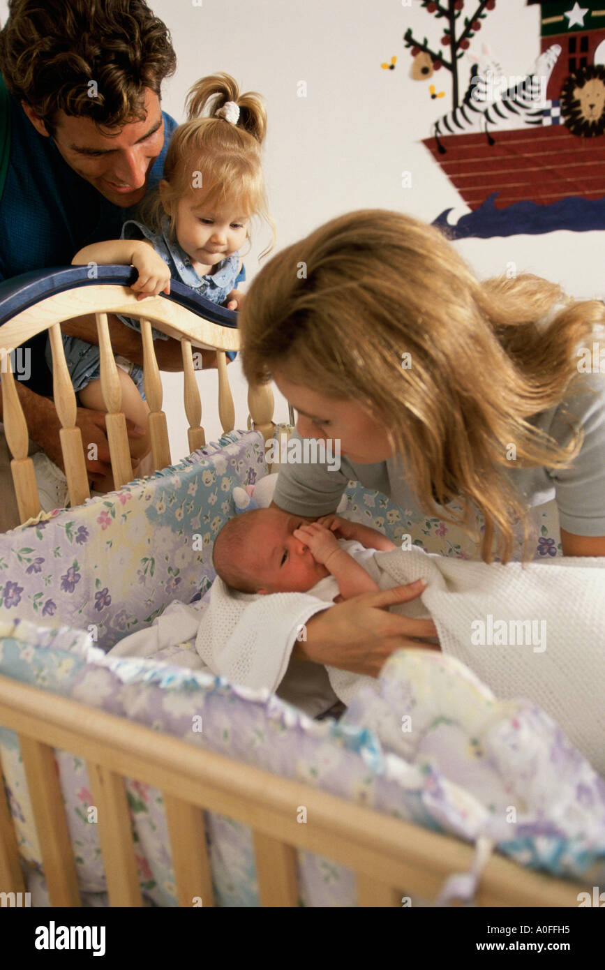 Parents looking at their baby girl in a crib Stock Photo - Alamy