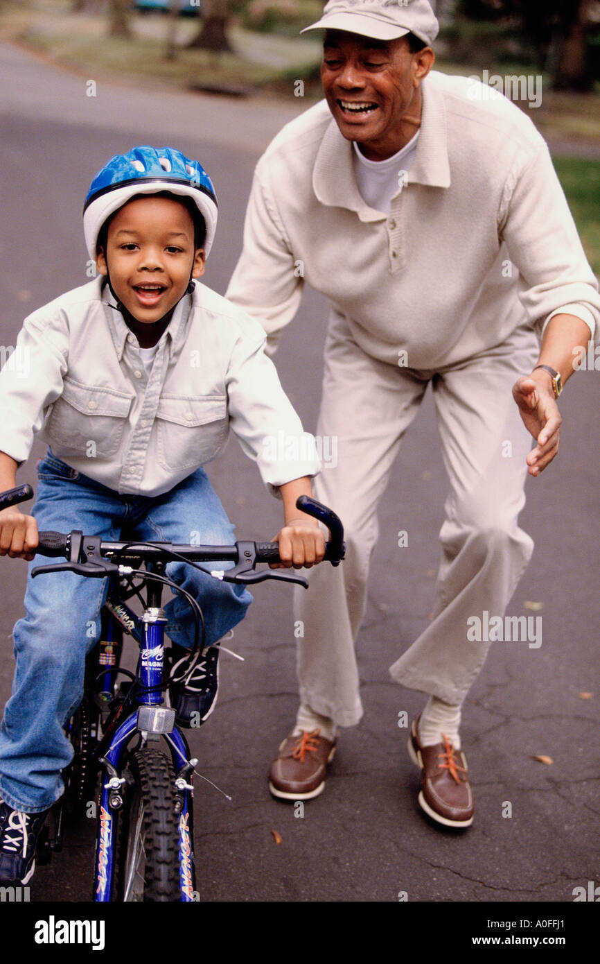 Grandfather helping his grandson ride a bicycle Stock Photo - Alamy