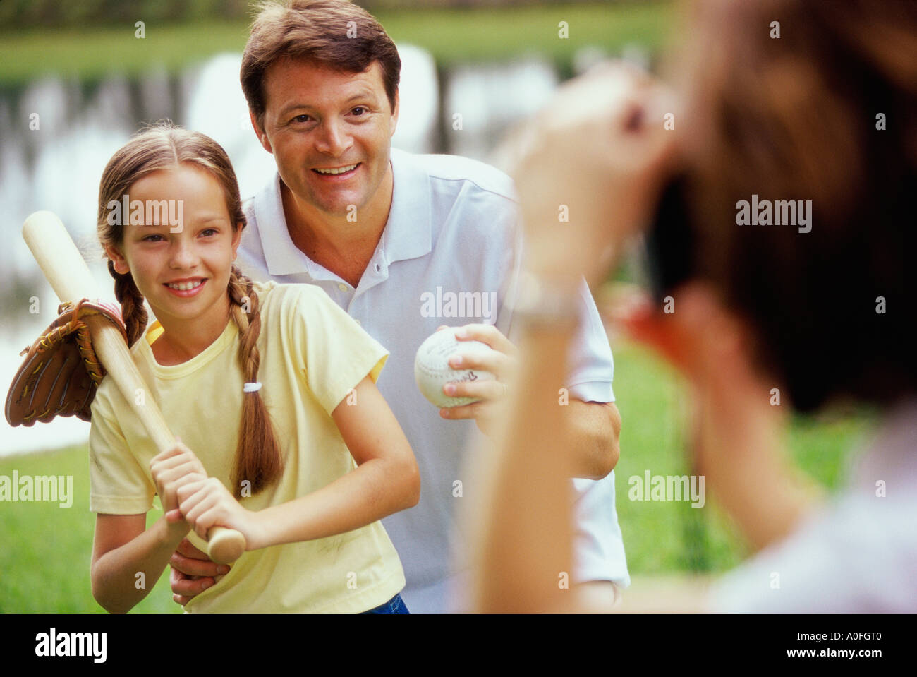 Father holding a baseball bat standing with his daughter Stock Photo ...