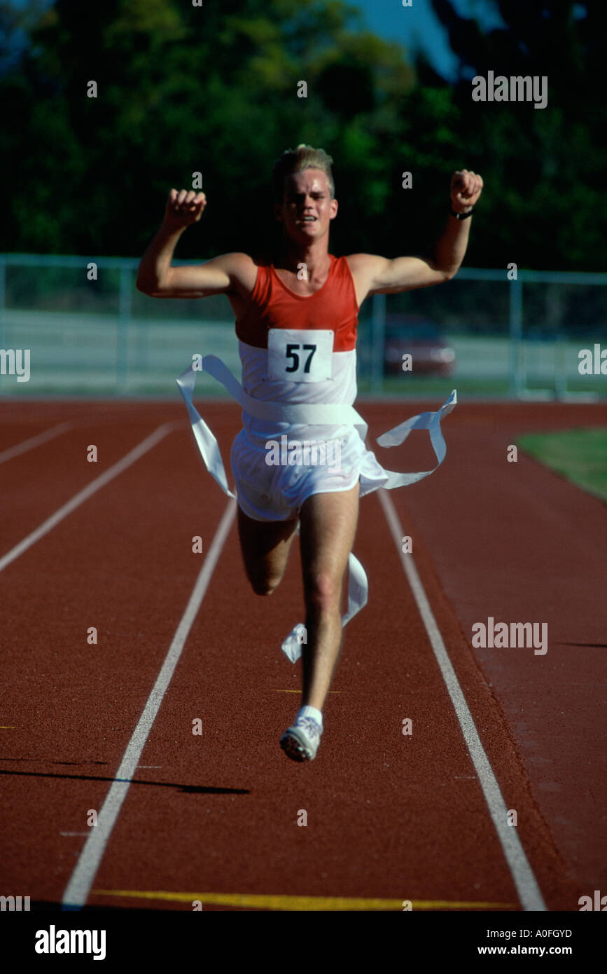 Portrait of a male runner crossing the finishing line with his arms ...