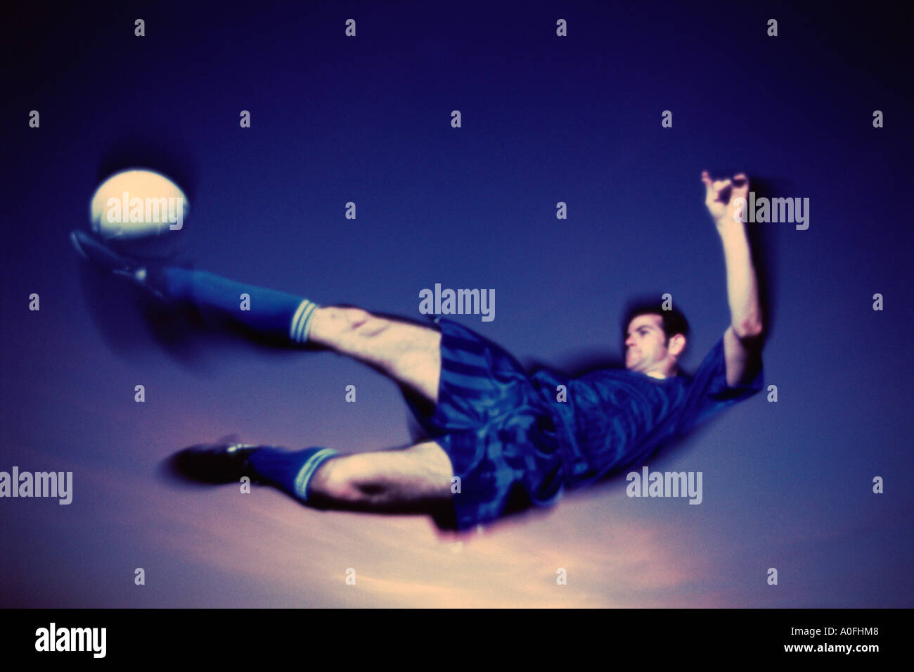 Young man kicking a soccer ball in mid air Stock Photo - Alamy