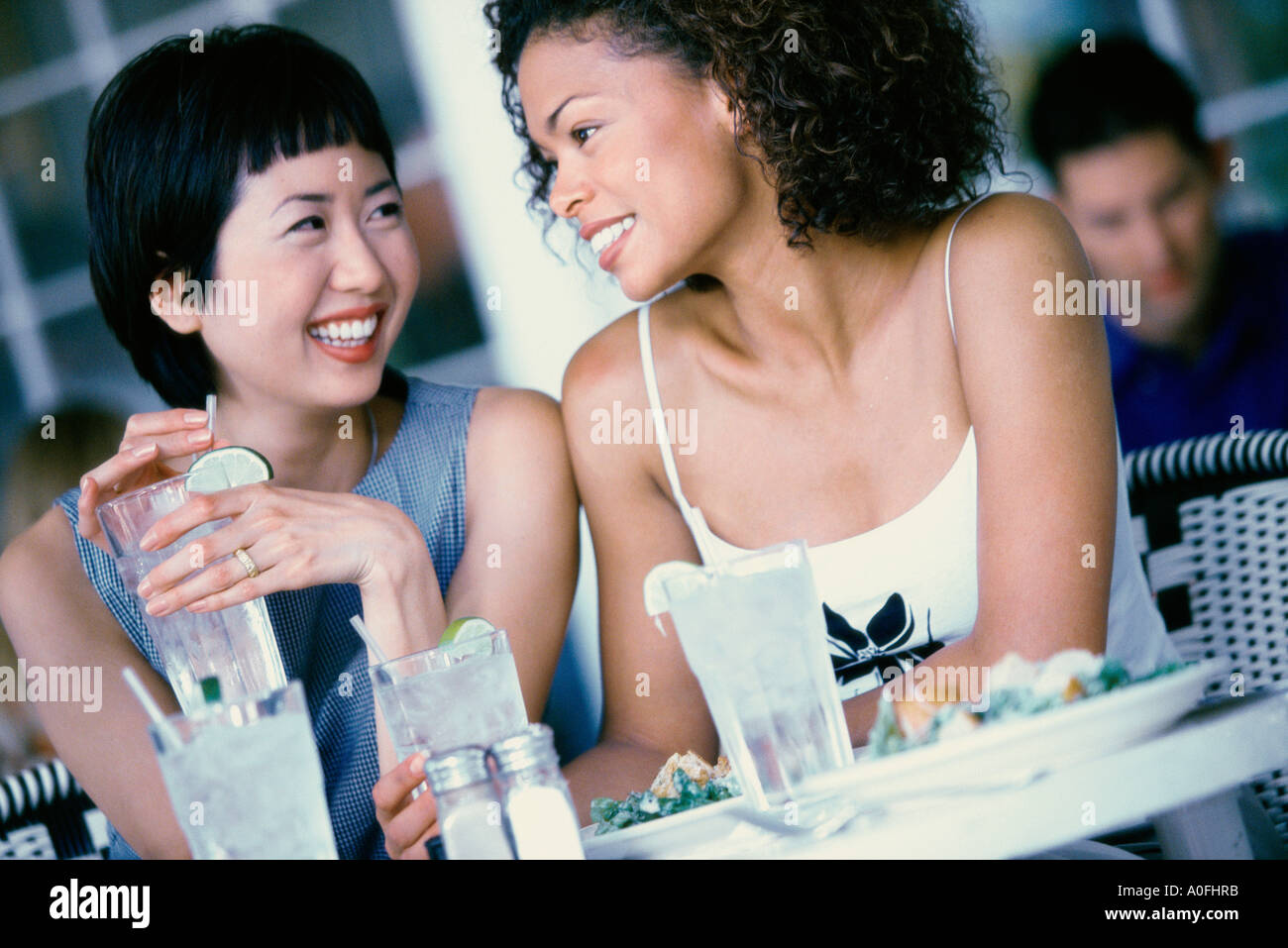 Two young women seated at a table smiling Stock Photo - Alamy