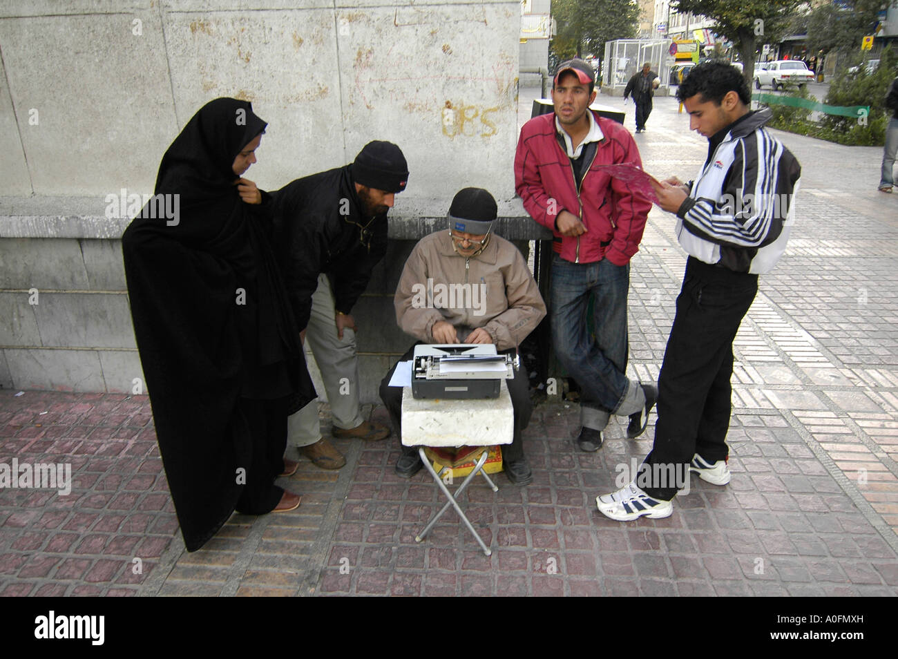 A clerk at work on an old typing machine, outside an Islamic court in ...