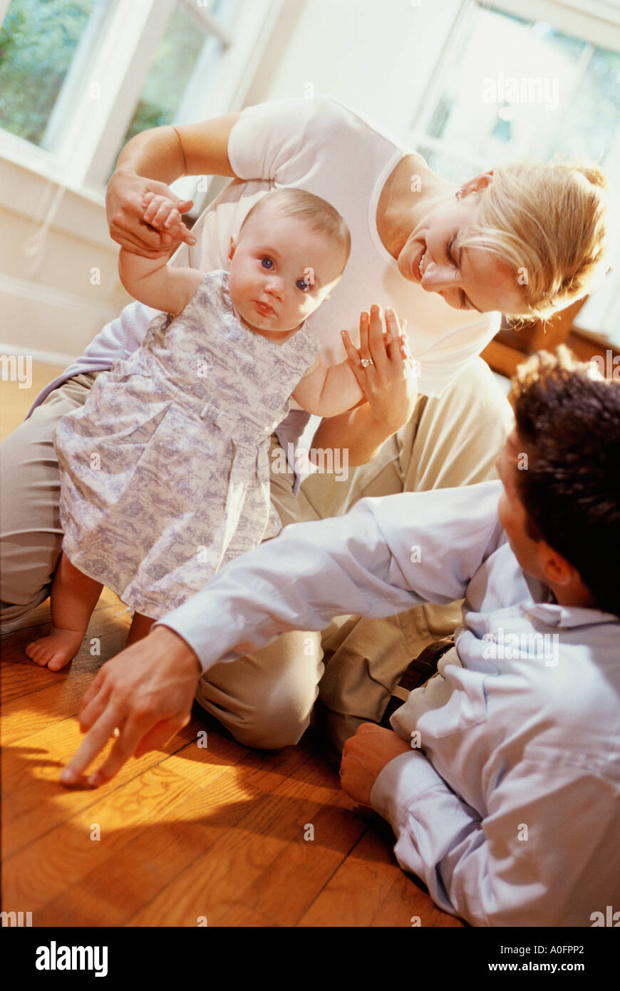 Parents helping their baby girl learn how to walk Stock Photo - Alamy