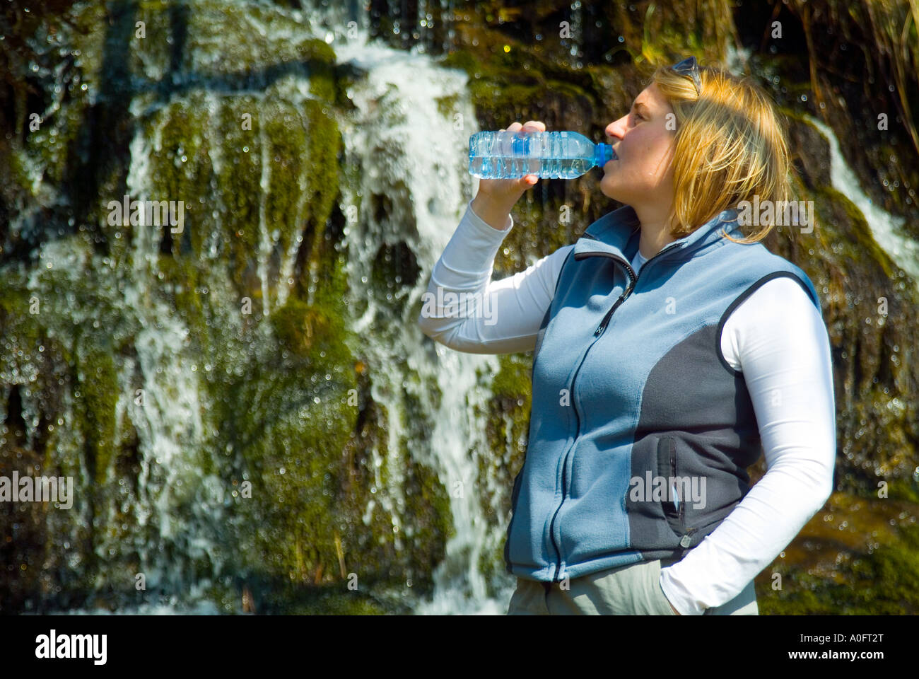 Young attractive woman drinking water from a bottle standing infront of ...