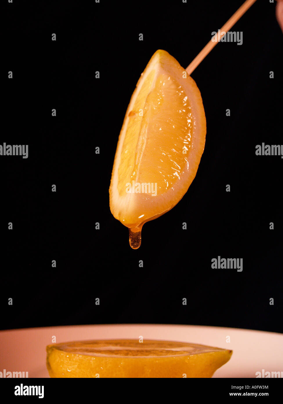 lemon with honey on a black ground Stock Photo - Alamy