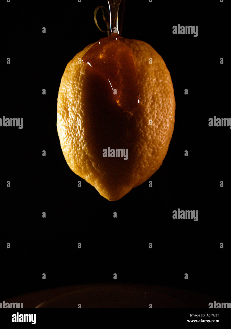 lemon with honey on a black ground Stock Photo - Alamy