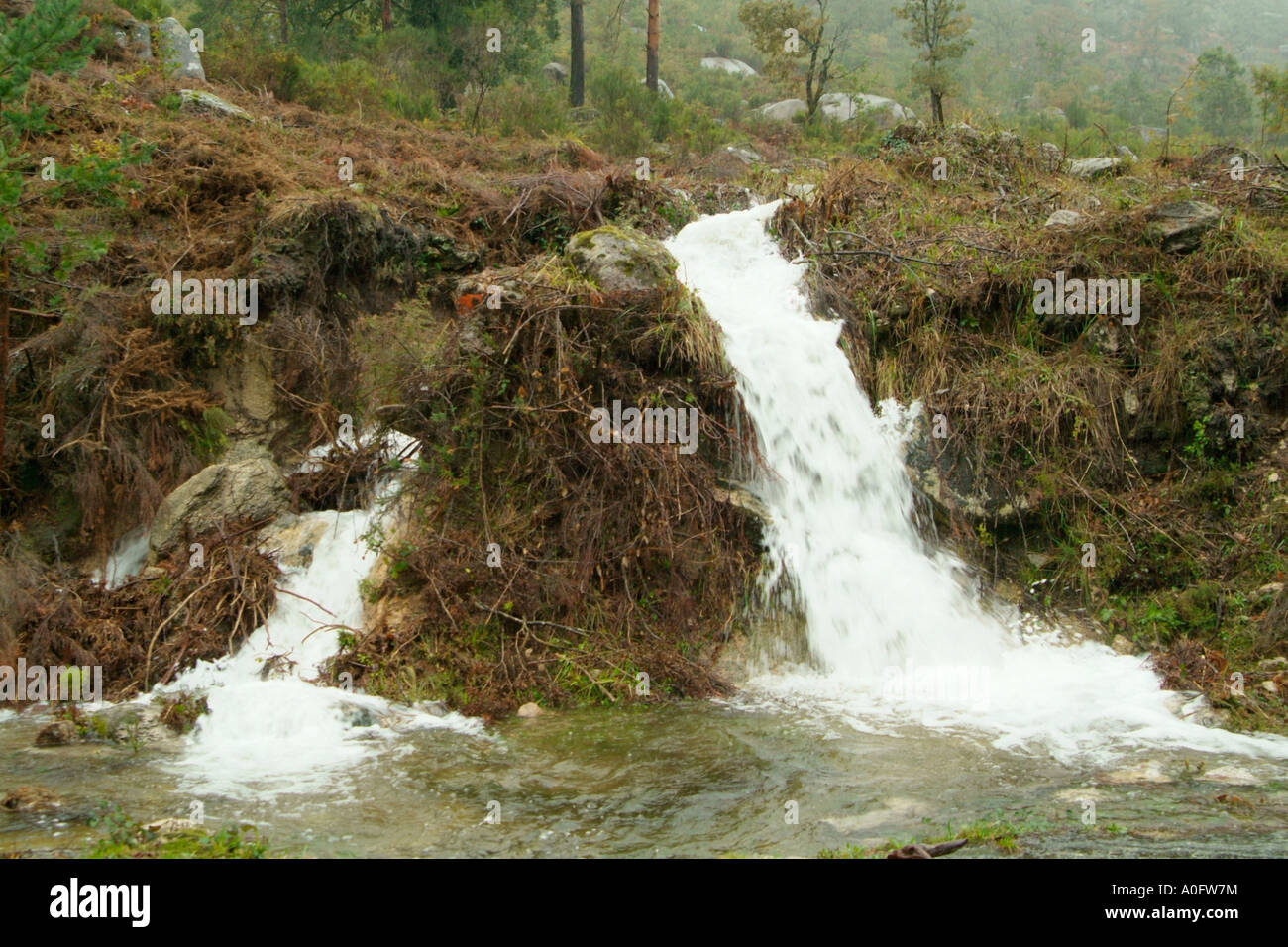 water flowing into a river forming a small waterfall Stock Photo - Alamy