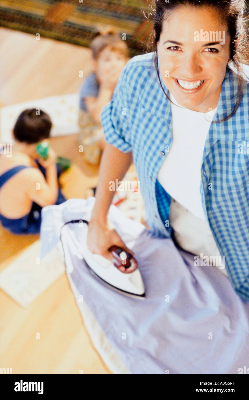 High angle view of a mother ironing clothes with her children playing ...